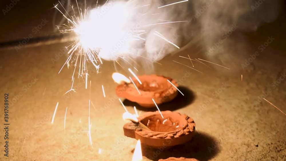 Happy Diwali - Lightning a sparkler with diya lamp during Diwali ...