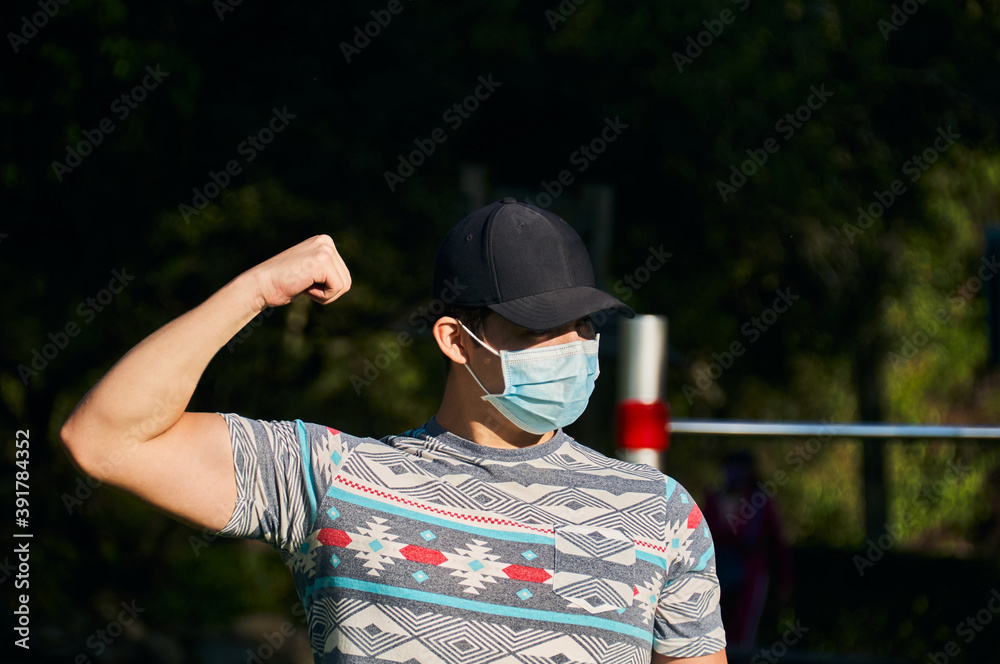 Young man wearing a face mask posing showing his muscles after his ...