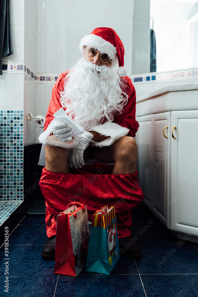 Santa Claus sitting in the toilet bowl pooping and holding a roll of ...