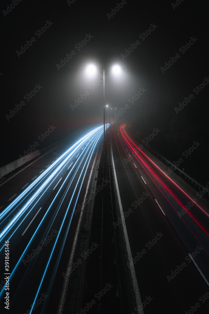 Vertical photo of cars light trails on a curved highway at night with ...