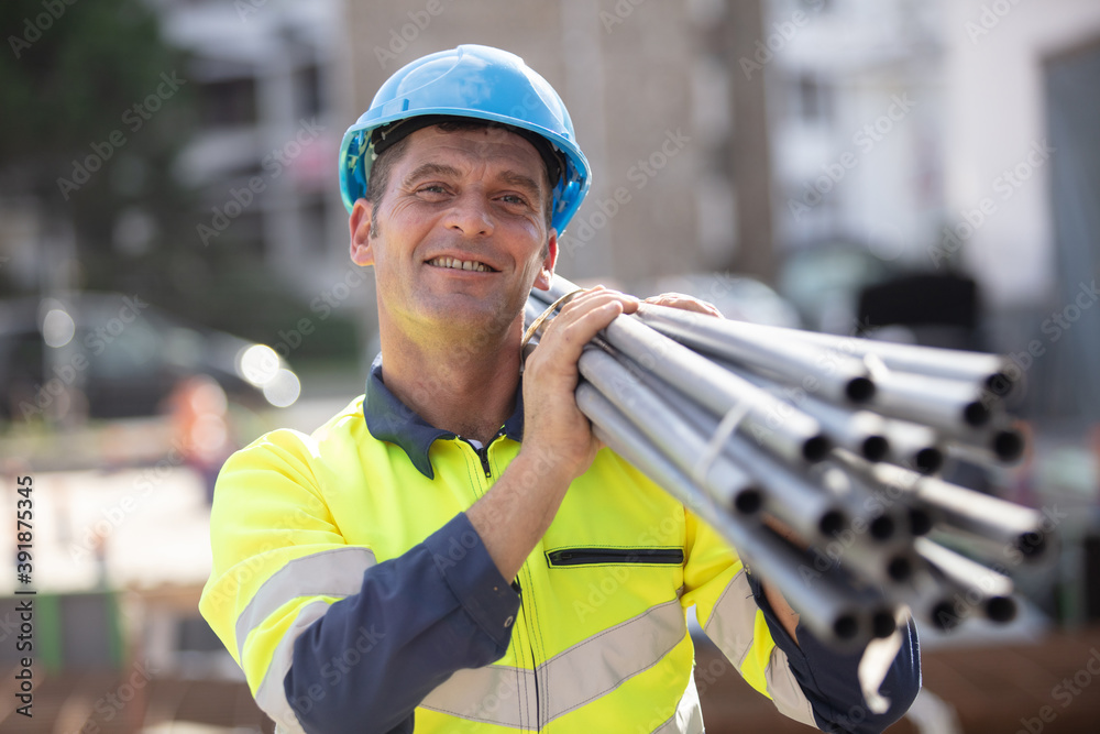 worker carrying pipes on his shoulder on construction site Stock-Foto ...