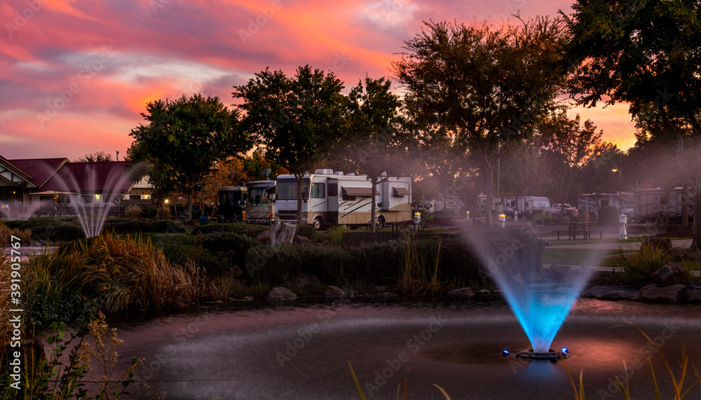 Camping at a Rv park with a water fountain with lights under a colorful ...