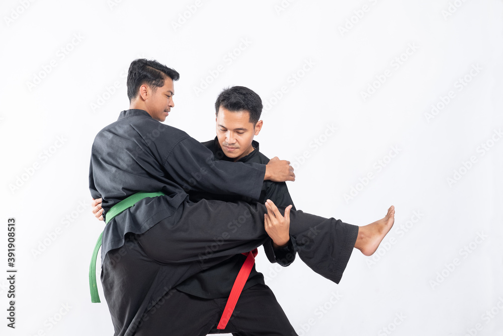 Two fighters in black pencak silat uniform fight in locks and slams in ...