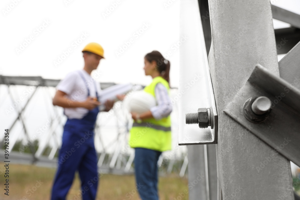 High voltage tower construction and blurred engineers on background ...