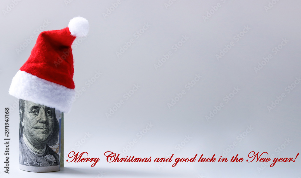 Santa's red cap is worn on a hundred-dollar bill rolled up with a ...