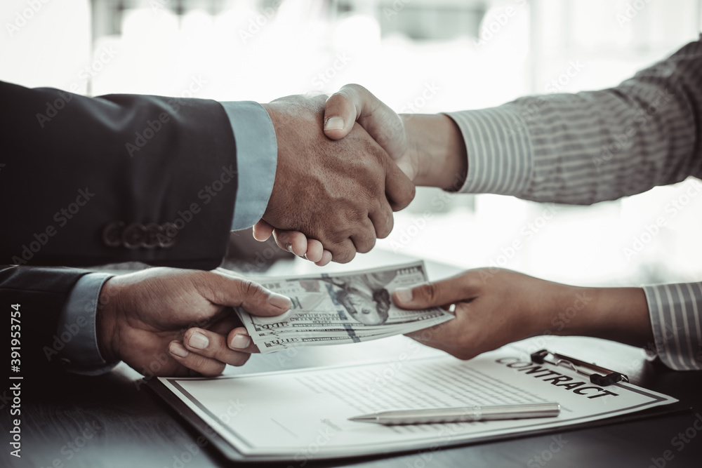 Business men shake hands and deliver dollar bills in a secret office ...