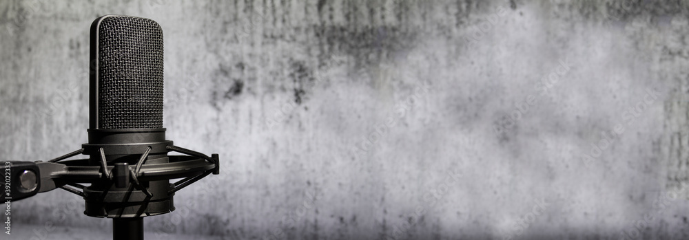 Studio black microphone on grey concrete wall background with copy ...