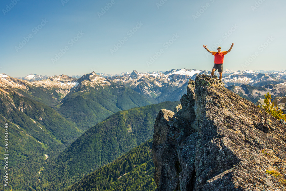 Hiker raises hands in celebration after reaching a mountain summit ...
