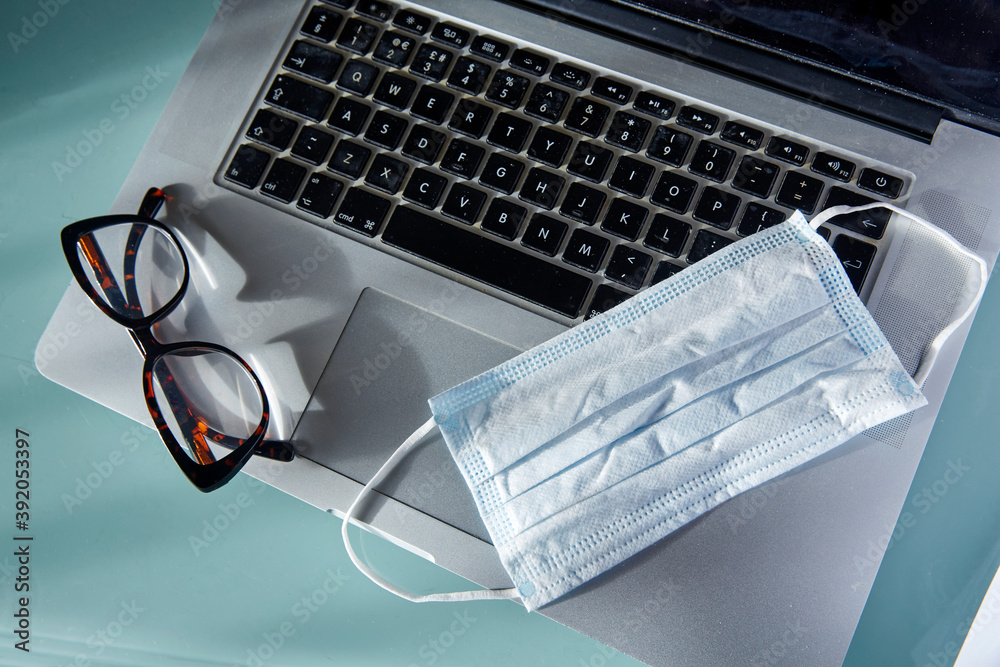 Still life of laptop with glasses and face mask in a home office in the ...