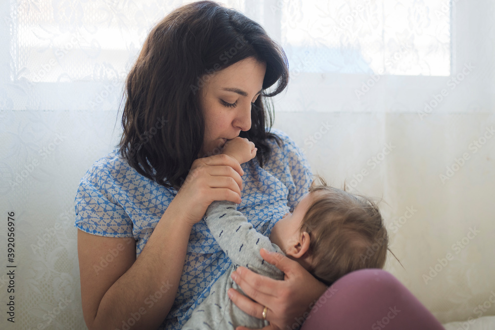 Foto de Tender loving mother kissing hand of baby while breastfeeding ...
