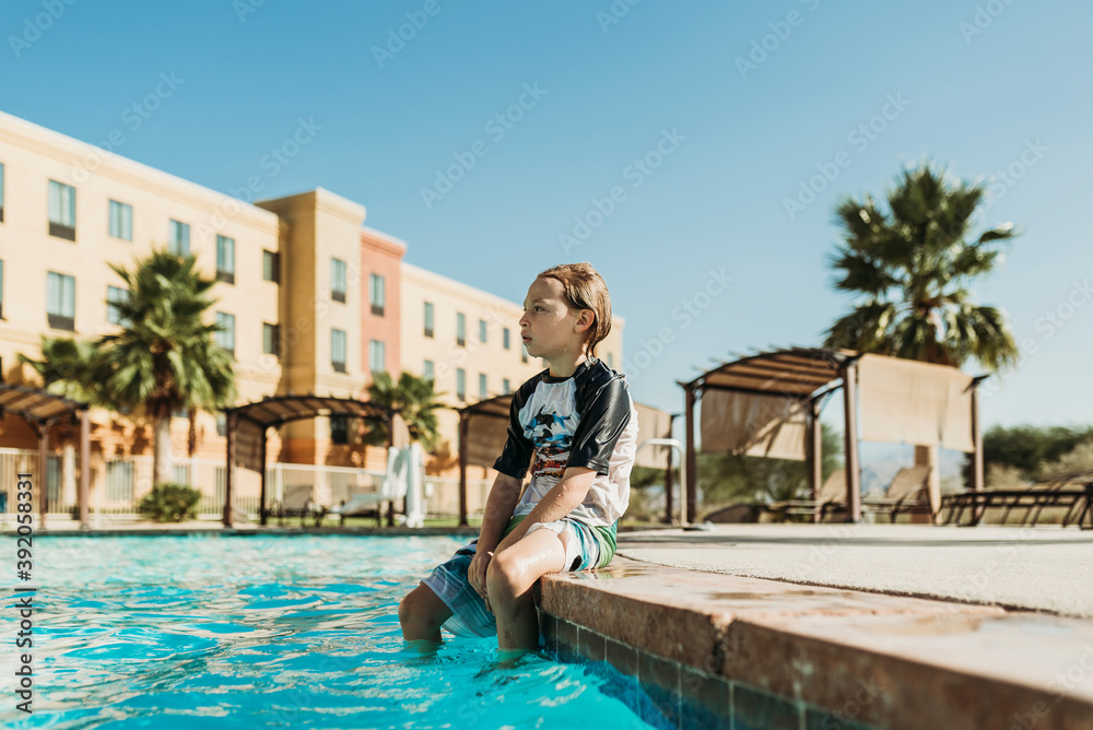 Young boy sitting on side of pool on vacation in Palm Springs Stock ...