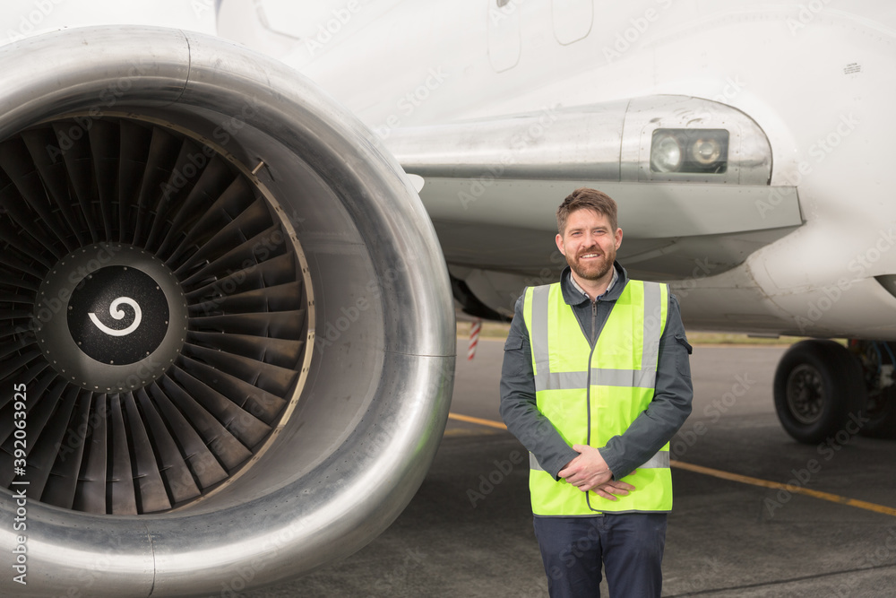 Positive engineer standing near plane Stock Photo | Adobe Stock