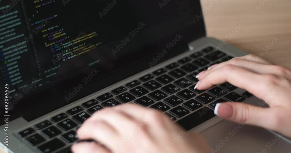 A young woman writes program code on a modern laptop, quickly typing on ...
