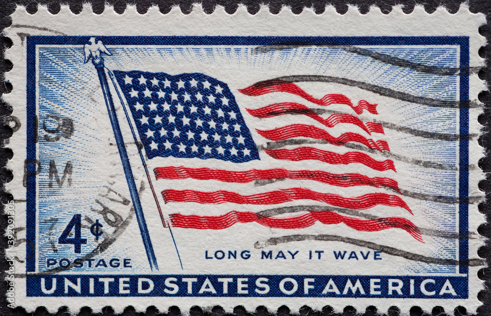 a postage stamp printed in the US showing The First US Flag with old ...