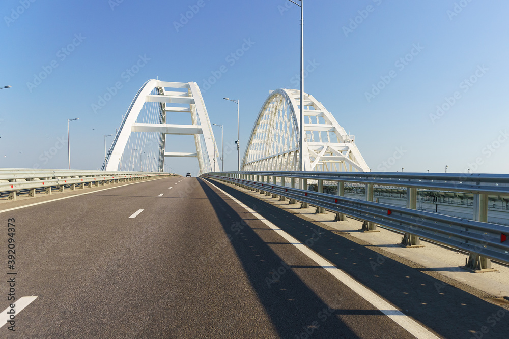 New asphalt road over the bridge over the Kerch Strait. White arches of ...