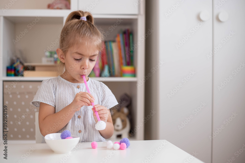 Little girl moving pom poms with the straw. Helpful fine motor practice ...