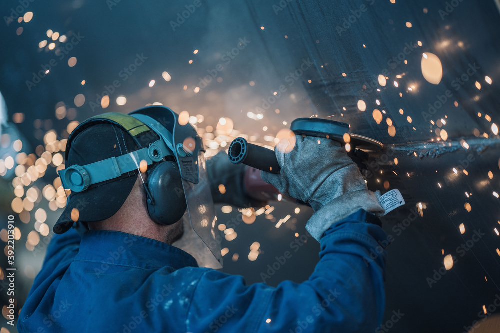 Worker cutting steel tanks with flying sparks Stock Photo | Adobe Stock
