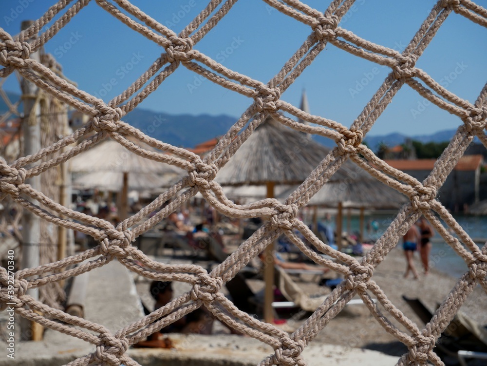 Through the decorative net you can see the beach where people, sea and ...