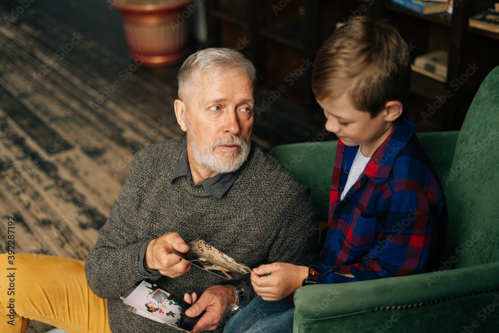Top view of handsome bearded grandfather showing photo to his grandson ...