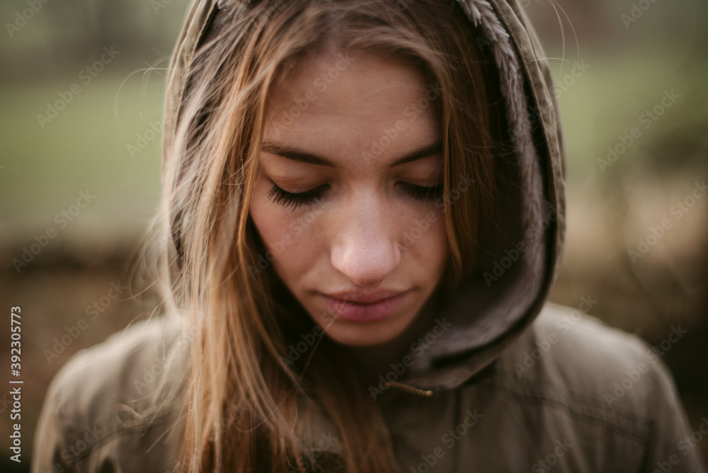 Calm sad woman in jacket and hood looking down Stock Photo | Adobe Stock