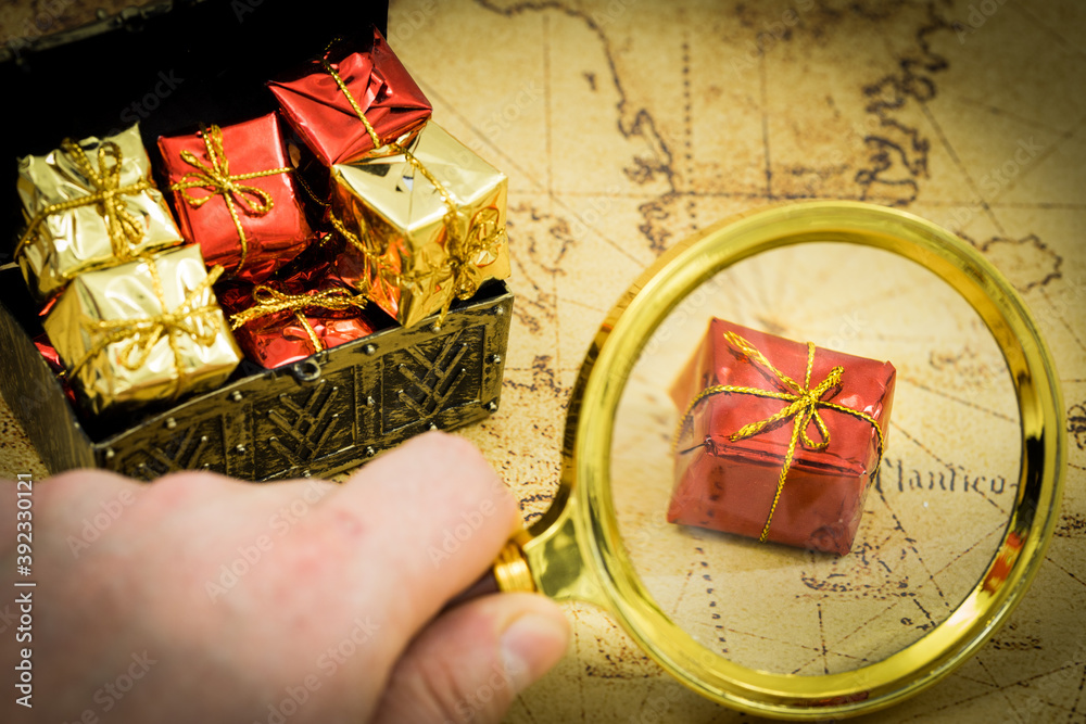 the treasure hunt. A hand with a magnifying glass above a chest full of ...