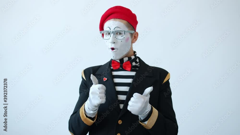 Portrait of surprised mime actor clapping hands smiling showing thumbs ...