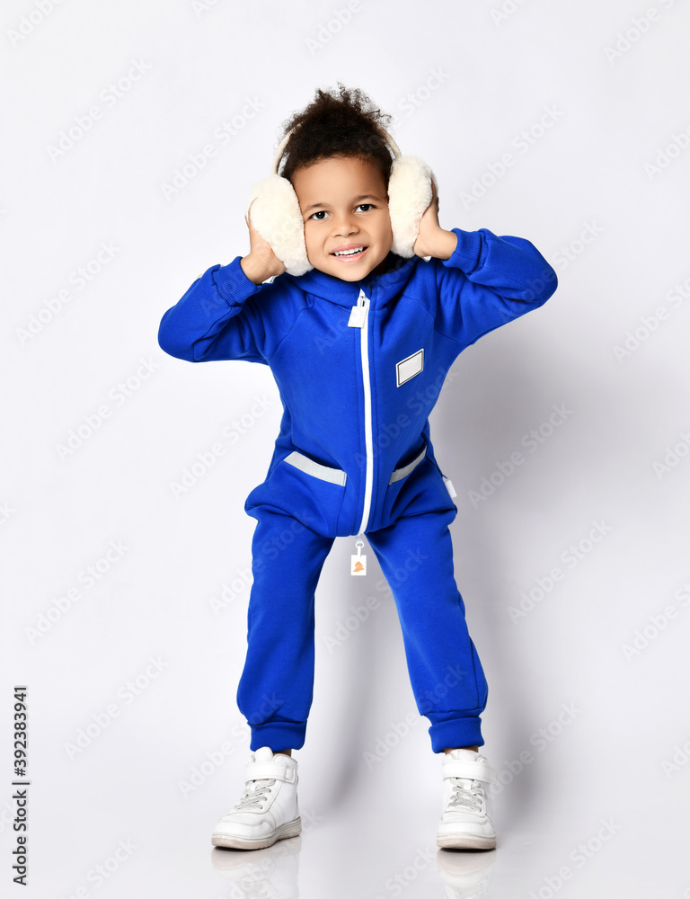 Portrait of cheerful smiling dark-skinned kid girl in blue overall ...