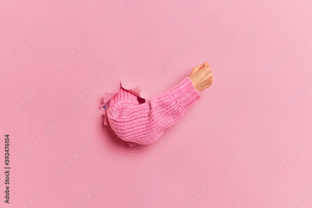 Faceless angry woman sticks out arm with clenched fist through paper ...