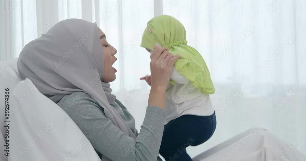 Beautiful young Islamic muslim Asian mother smiling in house life style ...