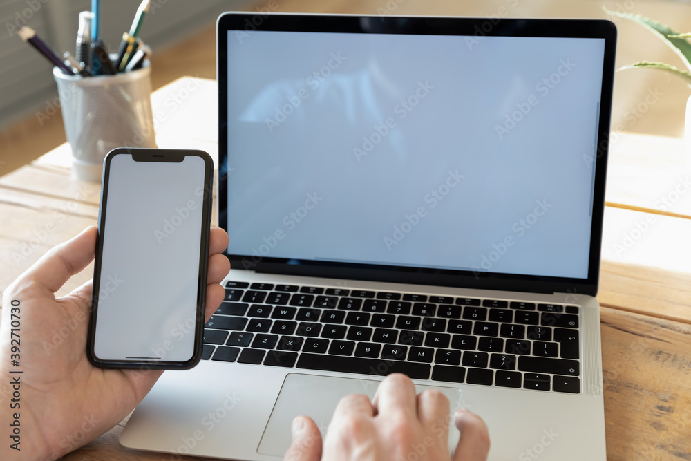 Business man sitting at desk using wireless computer holding smart ...