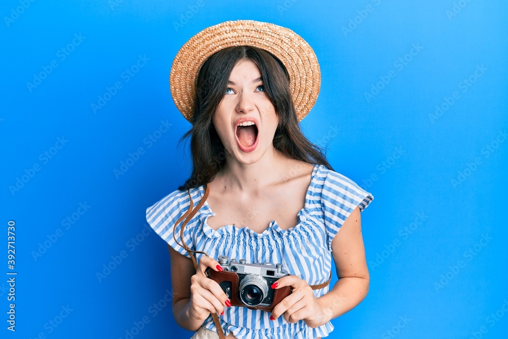 Young beautiful caucasian girl holding vintage camera angry and mad ...