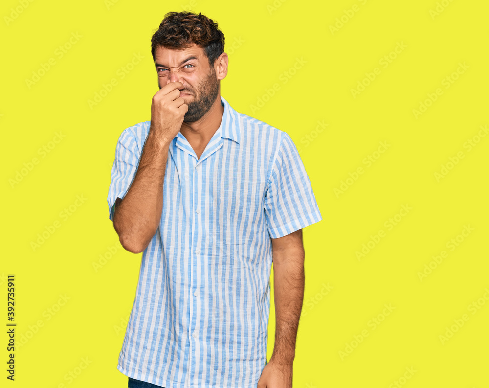 Handsome young man with beard wearing casual fresh shirt smelling ...