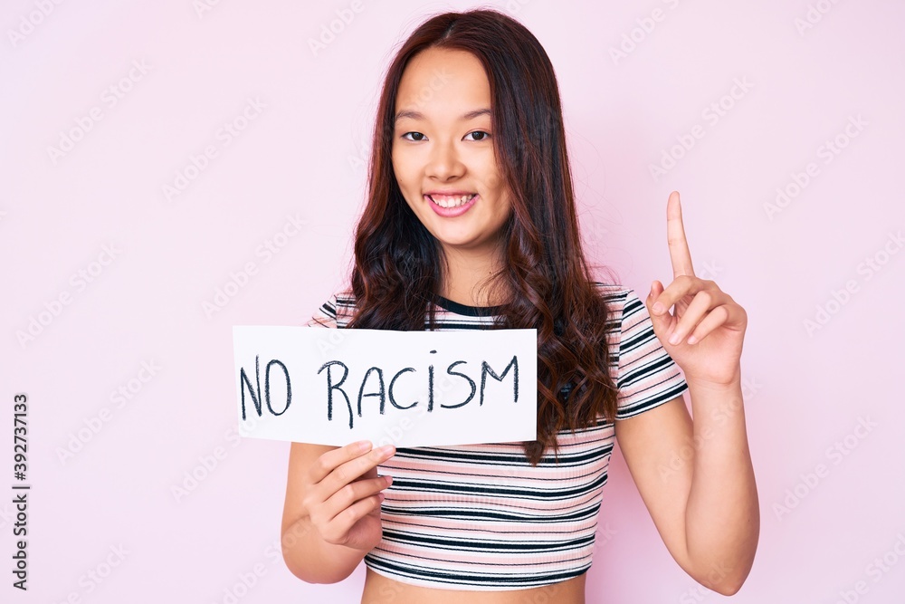 Young beautiful chinese girl holding no racism banner surprised with an ...