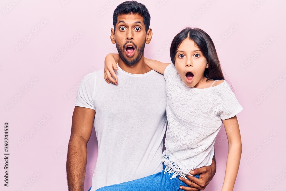 Latin father and daughter wearing casual clothes scared and amazed with ...