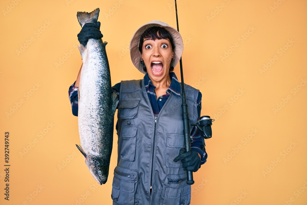 Beautiful brunettte fisher woman holding fishing rod and raw salmon ...