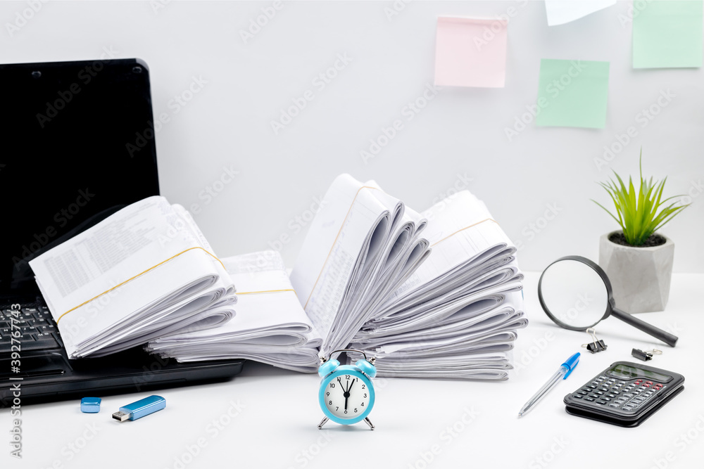 side view for workplace with huge heap paperwork and clock in front of ...