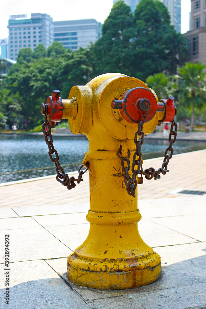 Typical old yellow fire hydrant with rusty chains on the sidewalk in ...