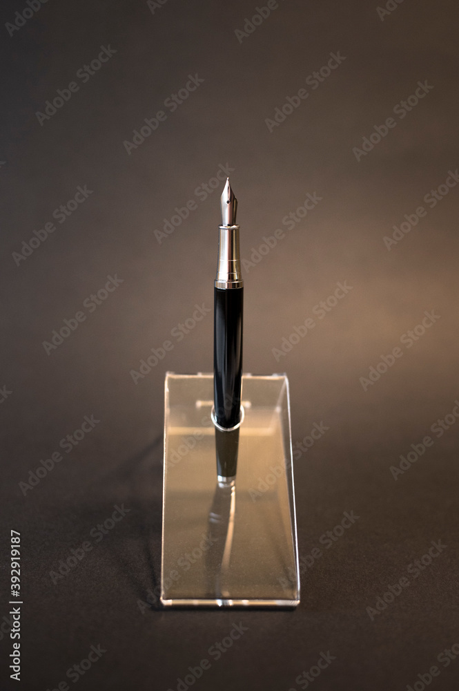 Black fountain pen with silver accessories on a black background ...