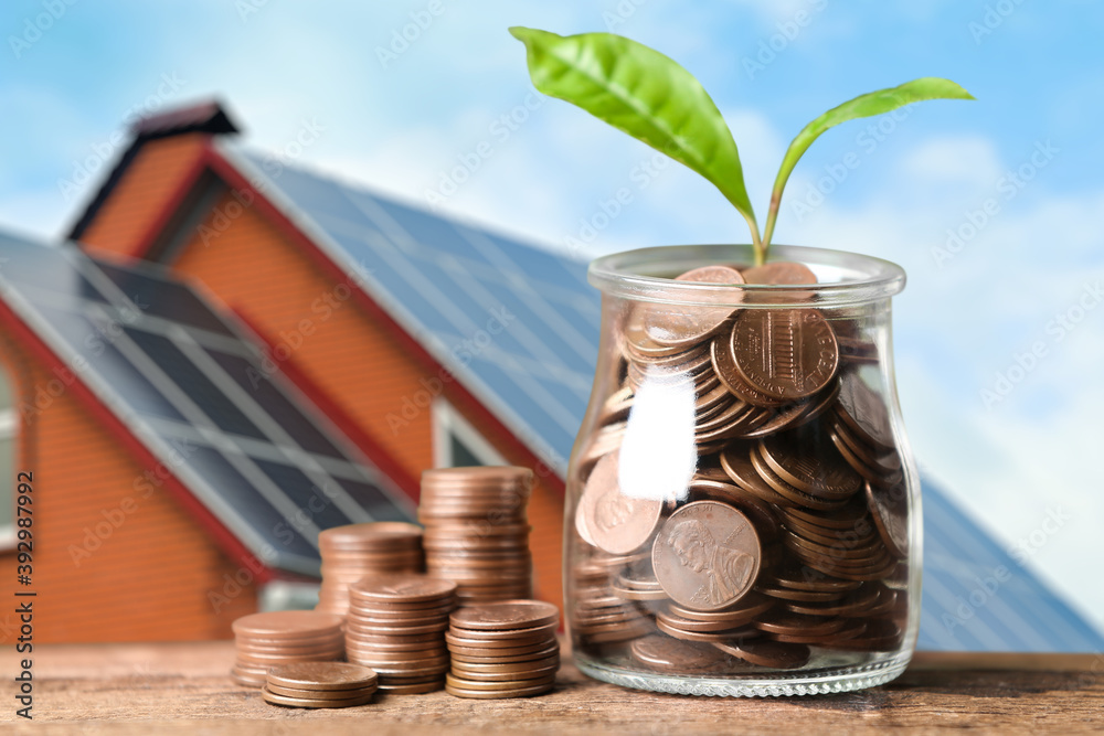 Money and sprout against house with installed solar panels on roof ...