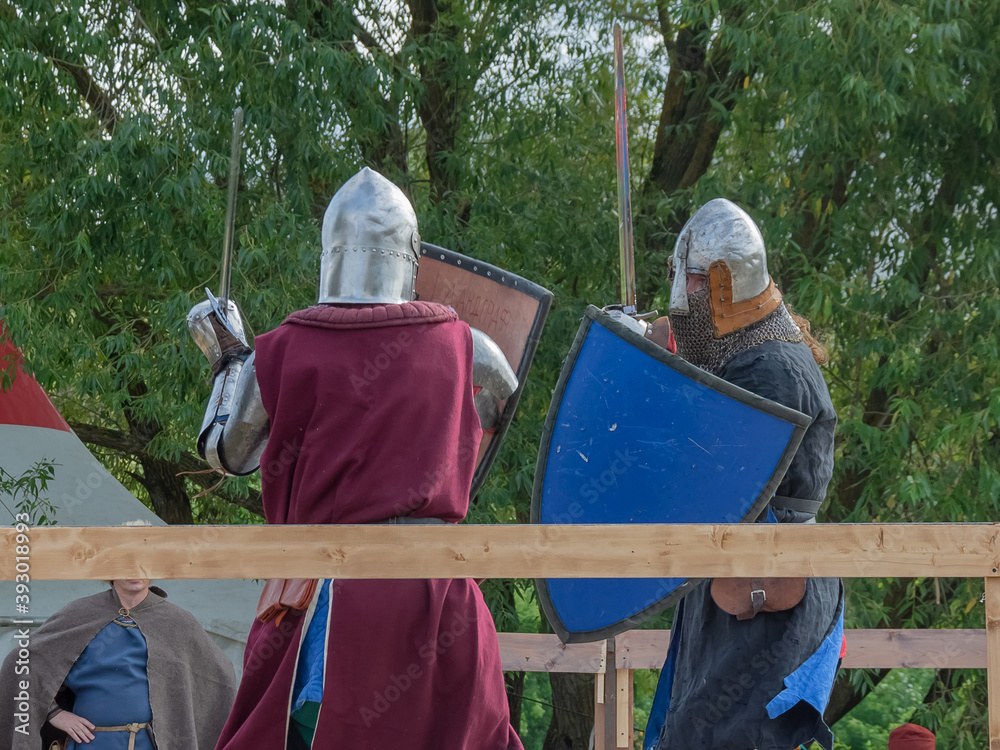 Two foot warriors in heavy medieval armor fight in the arena. Armed ...