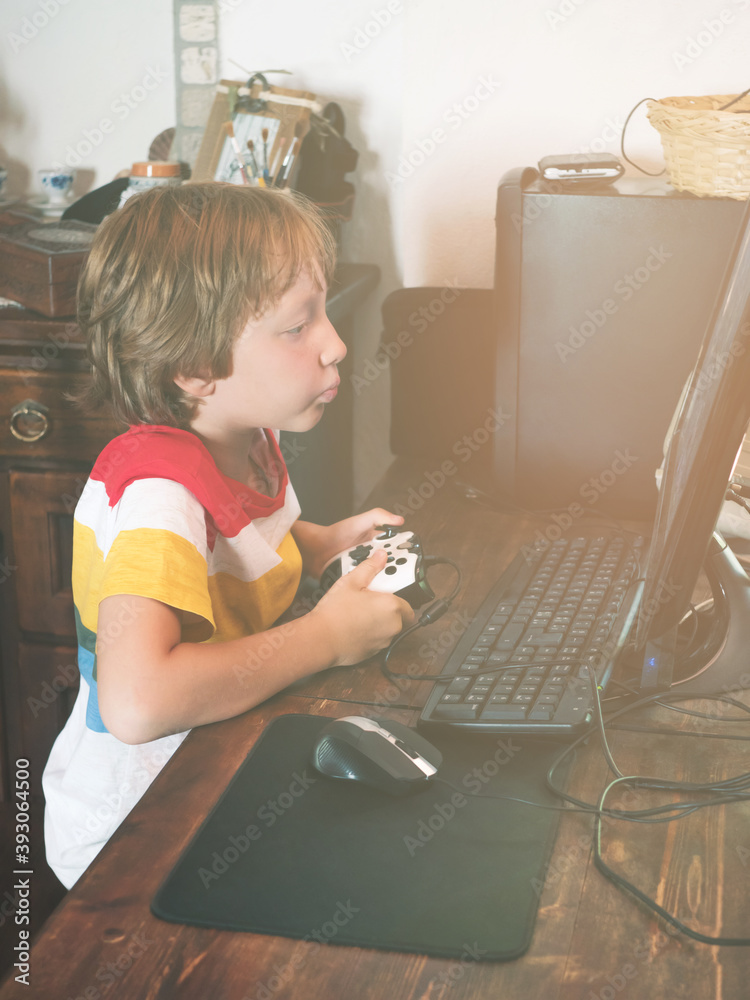 Little kid playing with joystick gamepad in front of PC at emulated ...