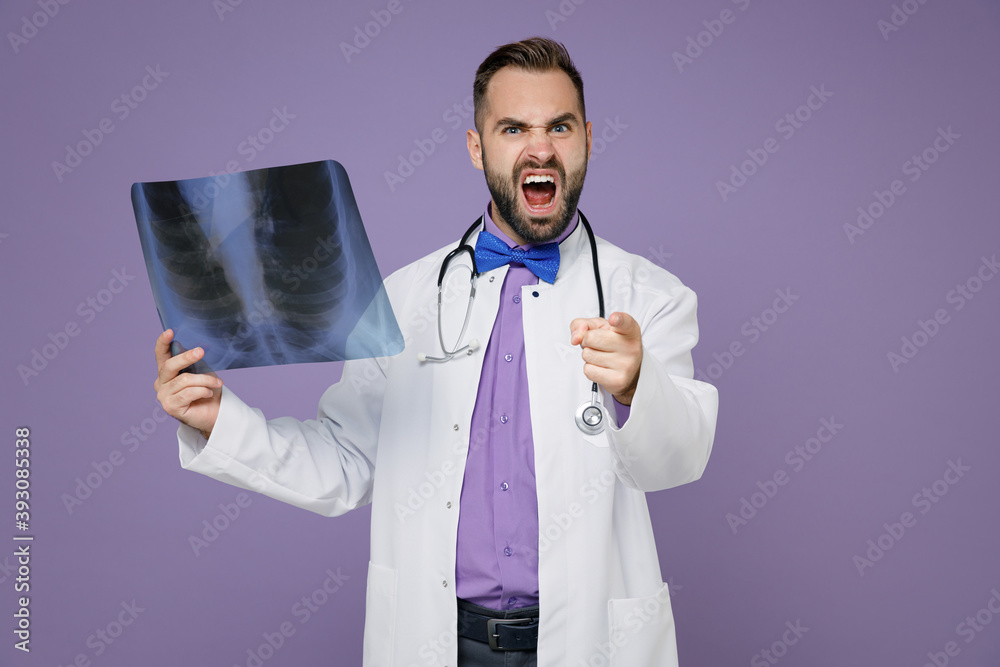 Irritated doctor man in medical gown stethoscope hold X-ray of lungs ...
