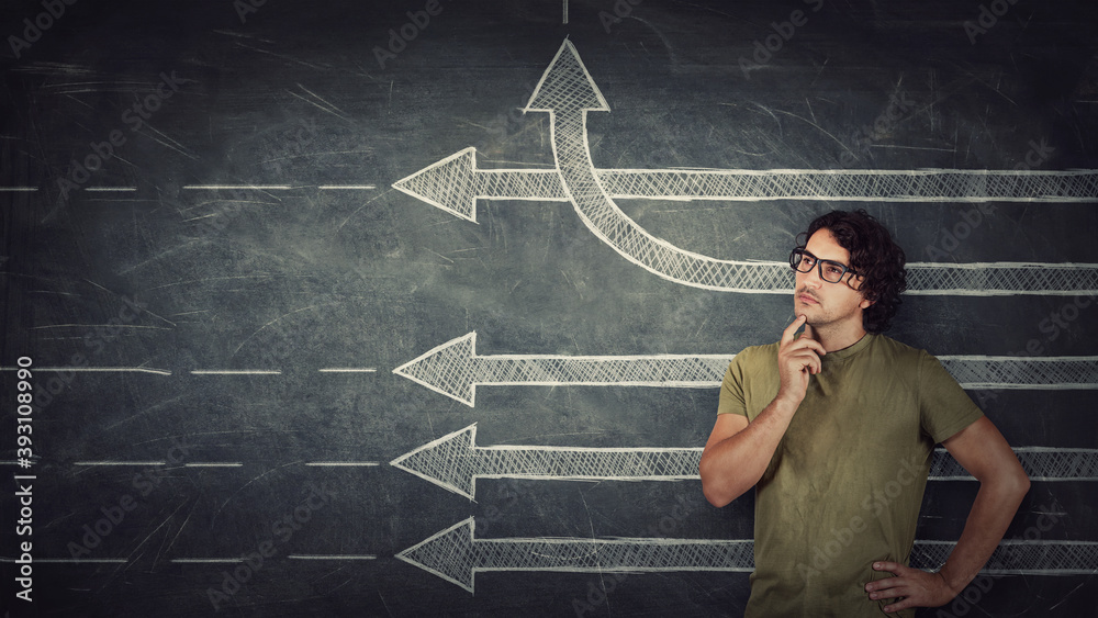 Pensive young man stands over chalkboard background with multiple ...