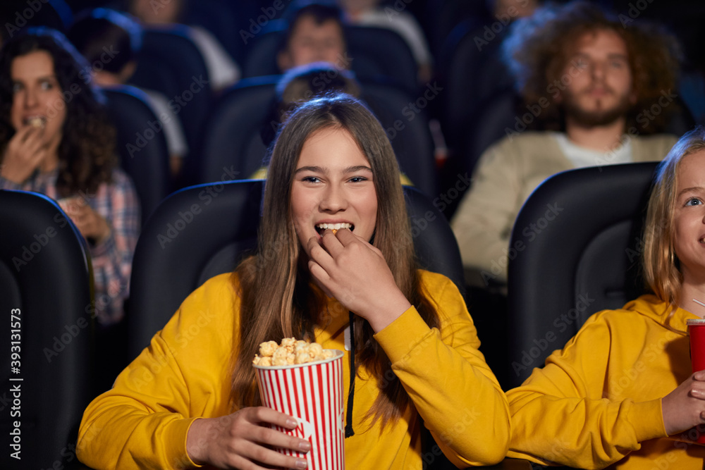 Young laughing girl eating popcorn in movie theater. Stock Photo ...