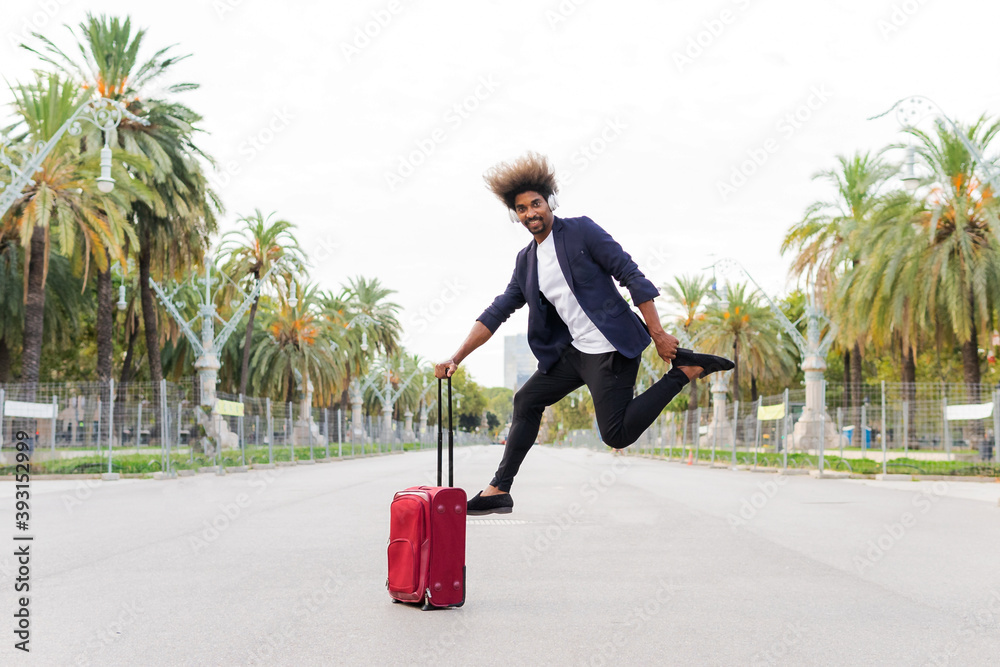 Young black man in a suit jumping and listening to music while ...