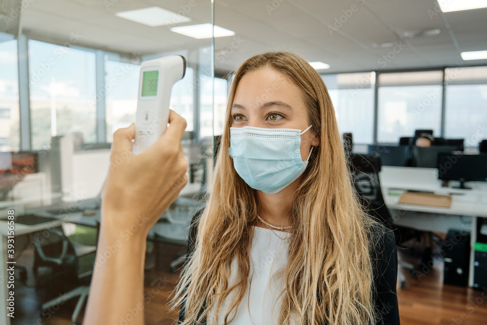Receptionist with thermometer gun checking body temperature of ...