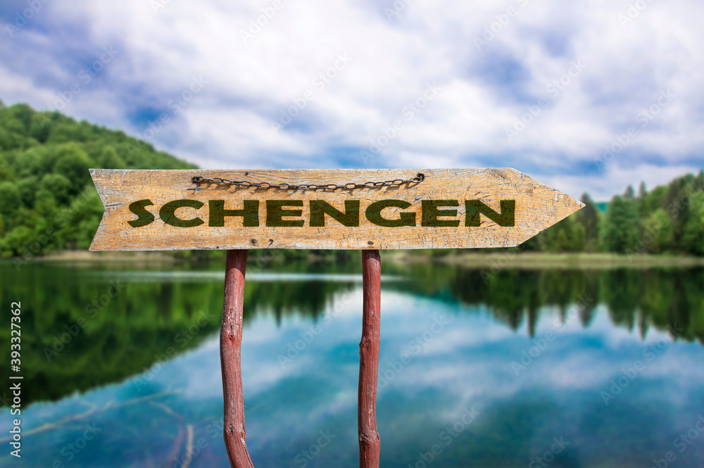 Schengen wooden arrow road sign against lake and forest background ...