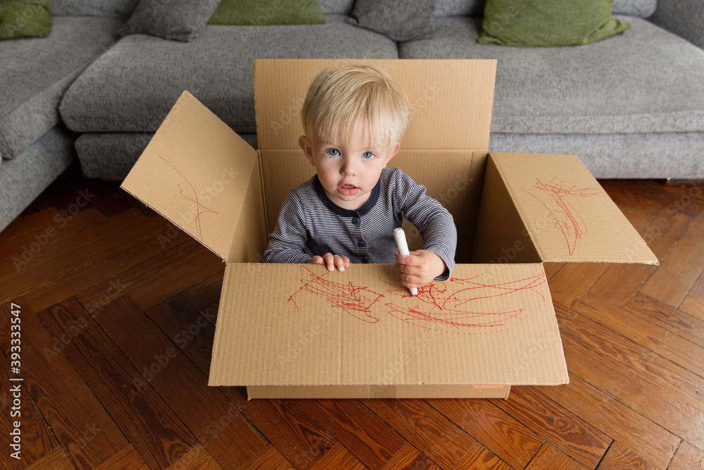 Cute baby boy drawing on cardboard box Stock Photo | Adobe Stock