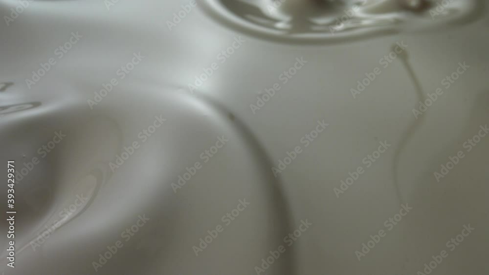 Close-up thick fresh milk is poured from top to bottom and spreads in ...