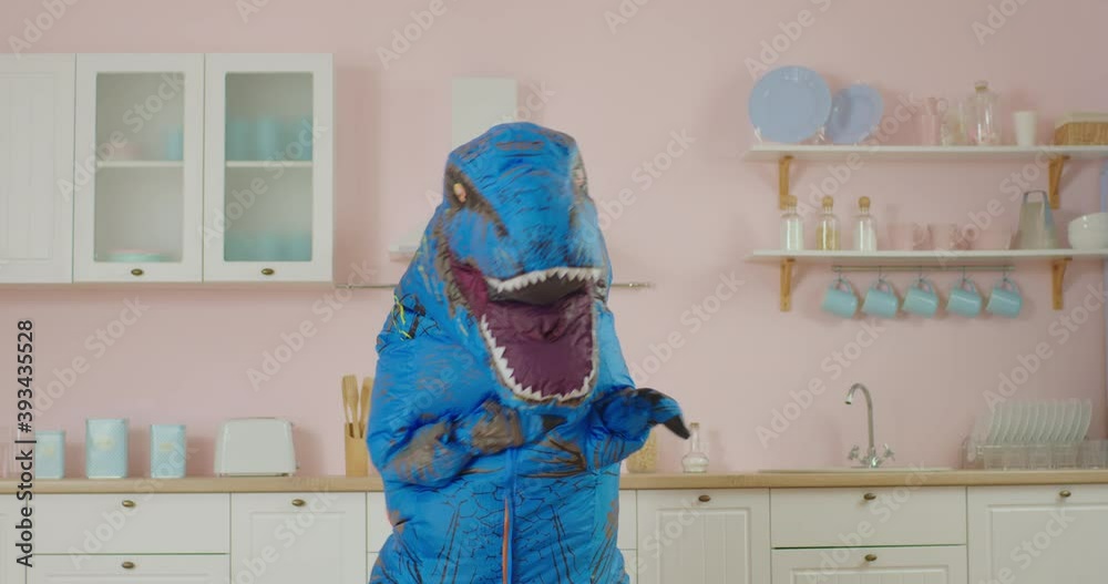 Funny dancing of blue dinosaur at pink kitchen. Comical movements of ...